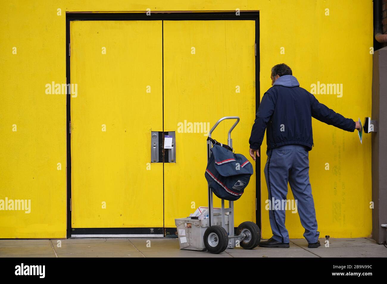 Portland, USA. 24th Mar, 2020. A USPS postal worker makes a delivery to ...