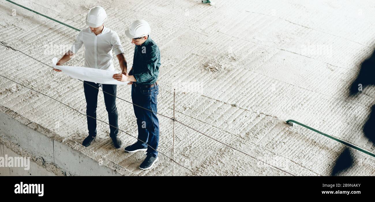Upper view portrait of two engineers looking at the building's plan ...