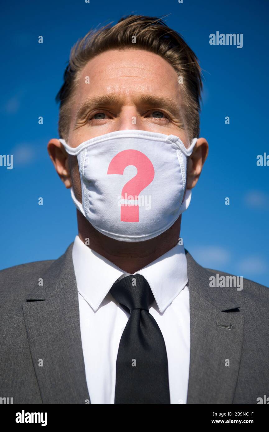 Businessman wearing surgical face mask with red question mark standing ...