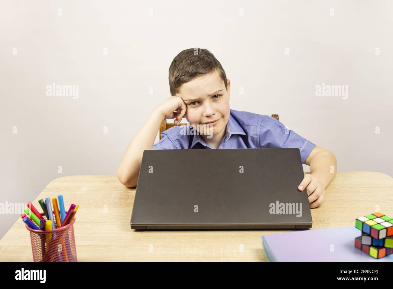 young guy looking at the camera. schoolboy boy sitting at a computer ...