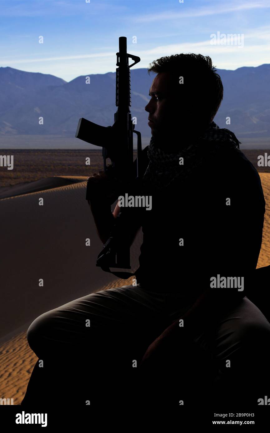 Silhouette of a male soldier resting in the shade on a desert and ...