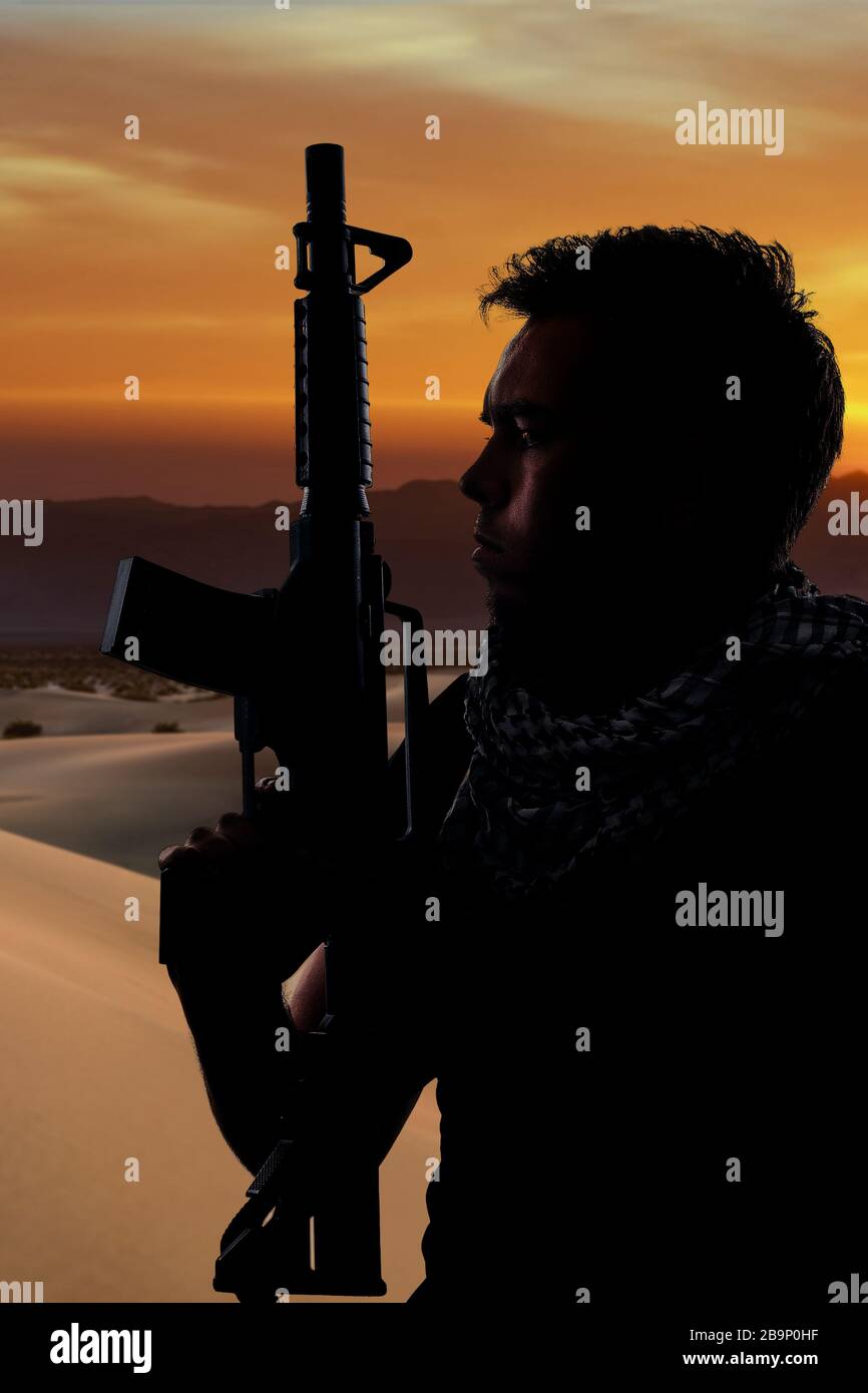 Silhouette of a male soldier resting in the shade on a desert and ...