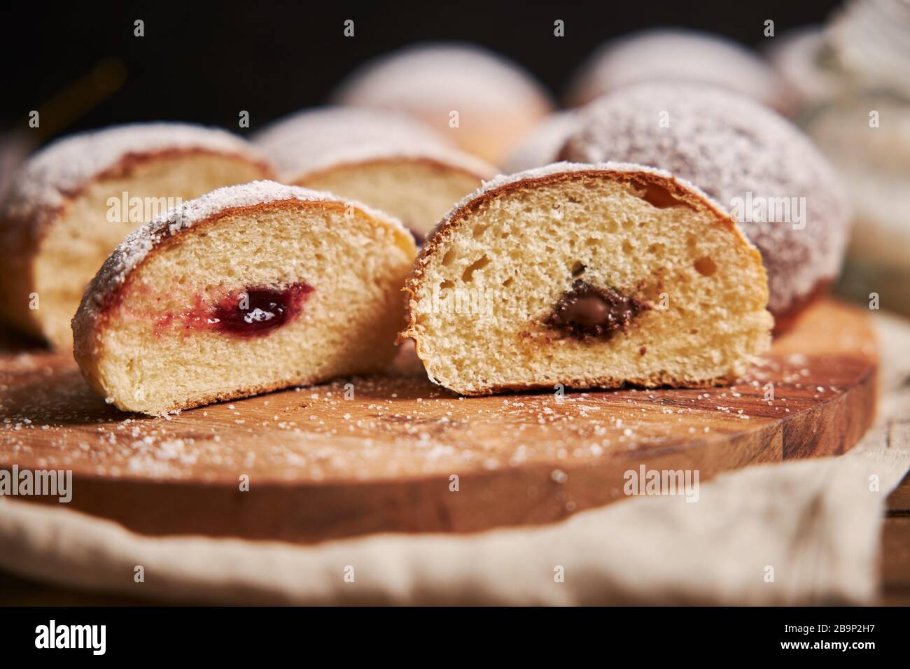 Closeup of fluffy cut doughnuts filled with jam on a tray under the ...