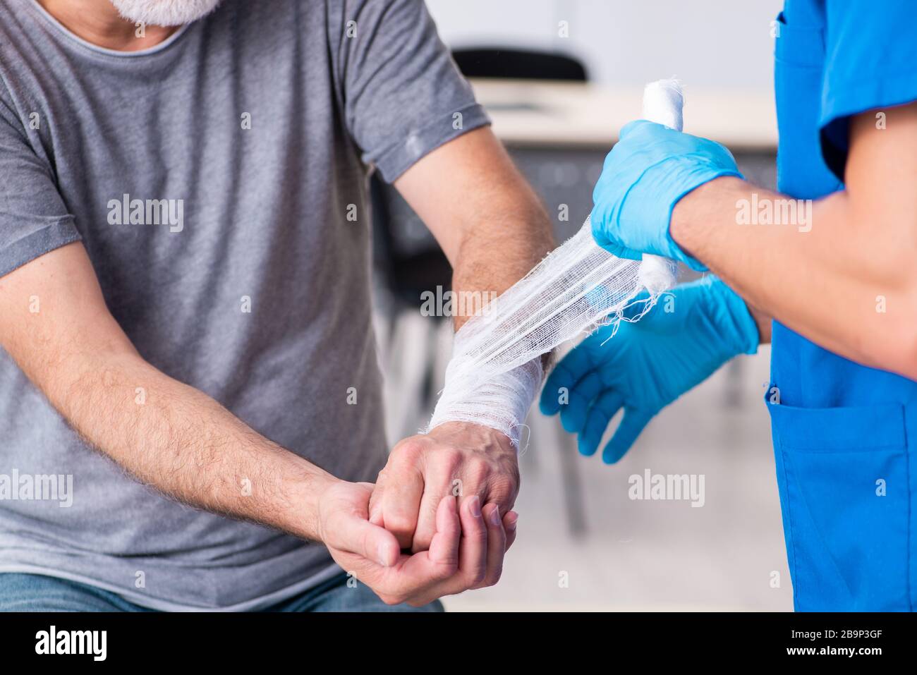 Young male doctor and old patient in first aid Stock Photo - Alamy