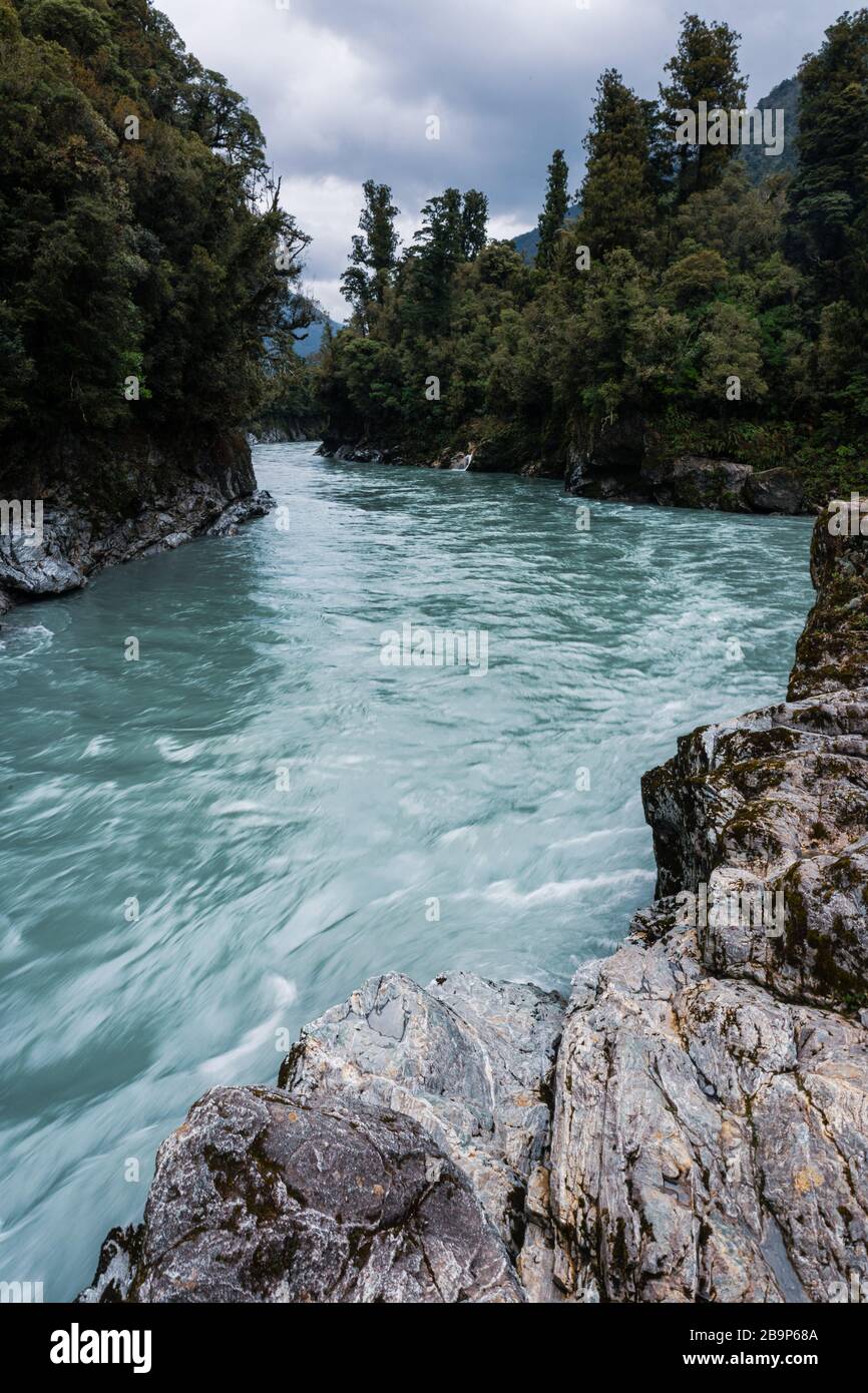 Vertical picture of a river surrounded by rocks and greenery under a ...