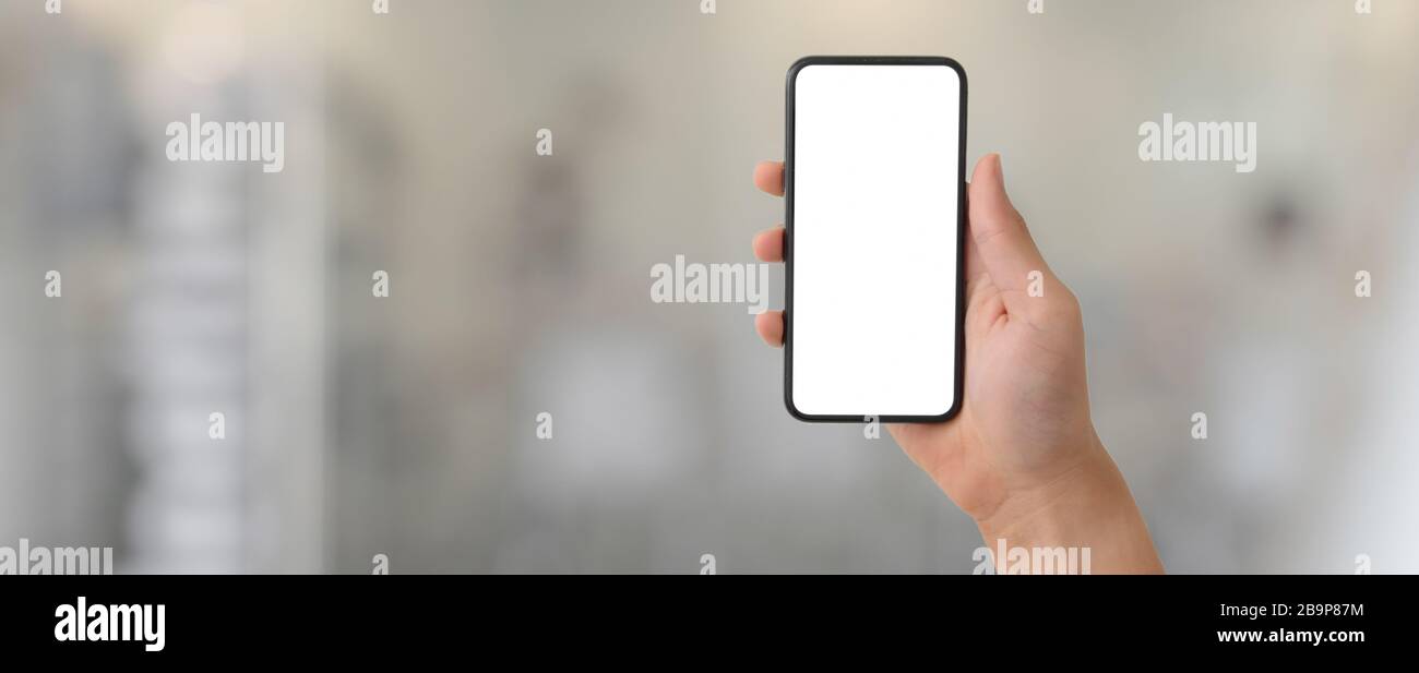 Cropped shot of a man showing blank screen smartphone in blurred glass ...