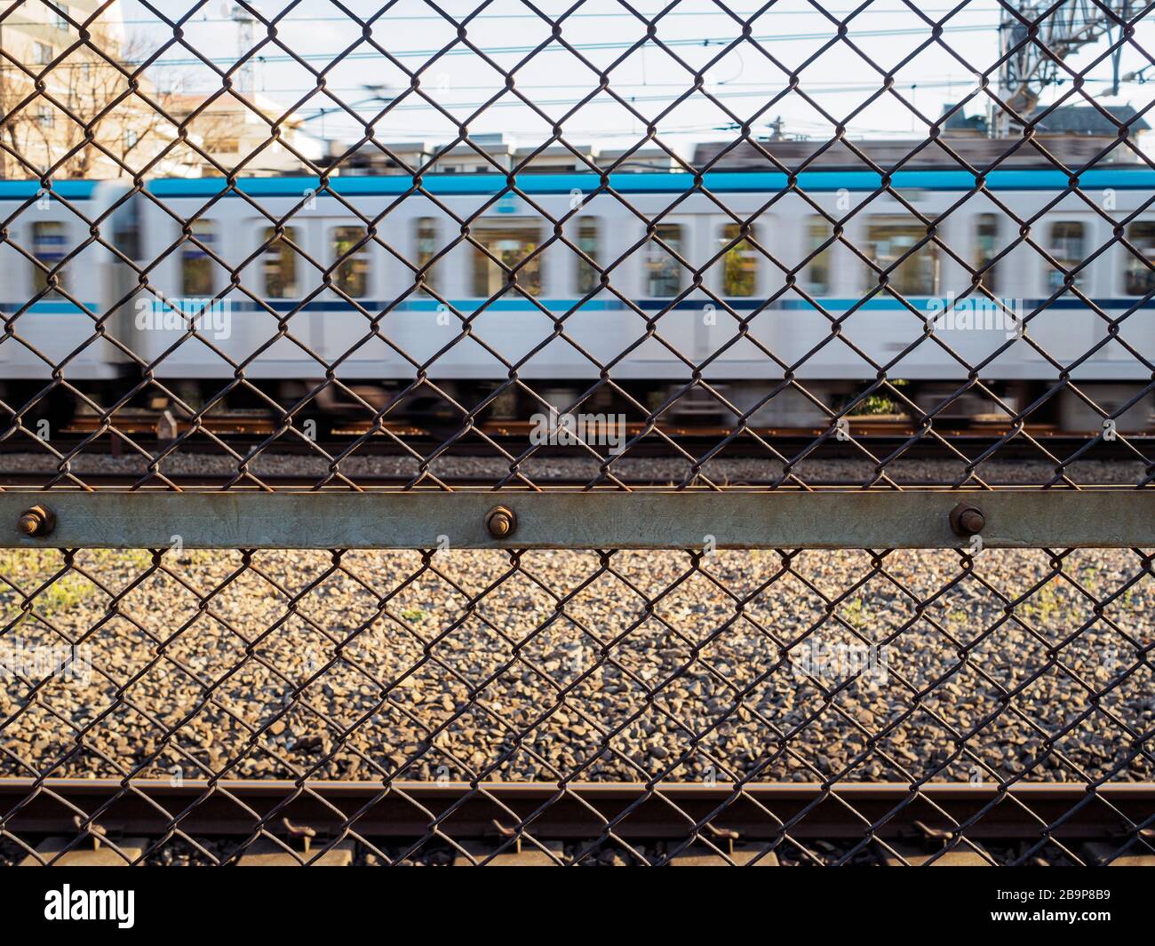 A Tozai metro train seen through a wire fence in Tokyo, Japan Stock ...