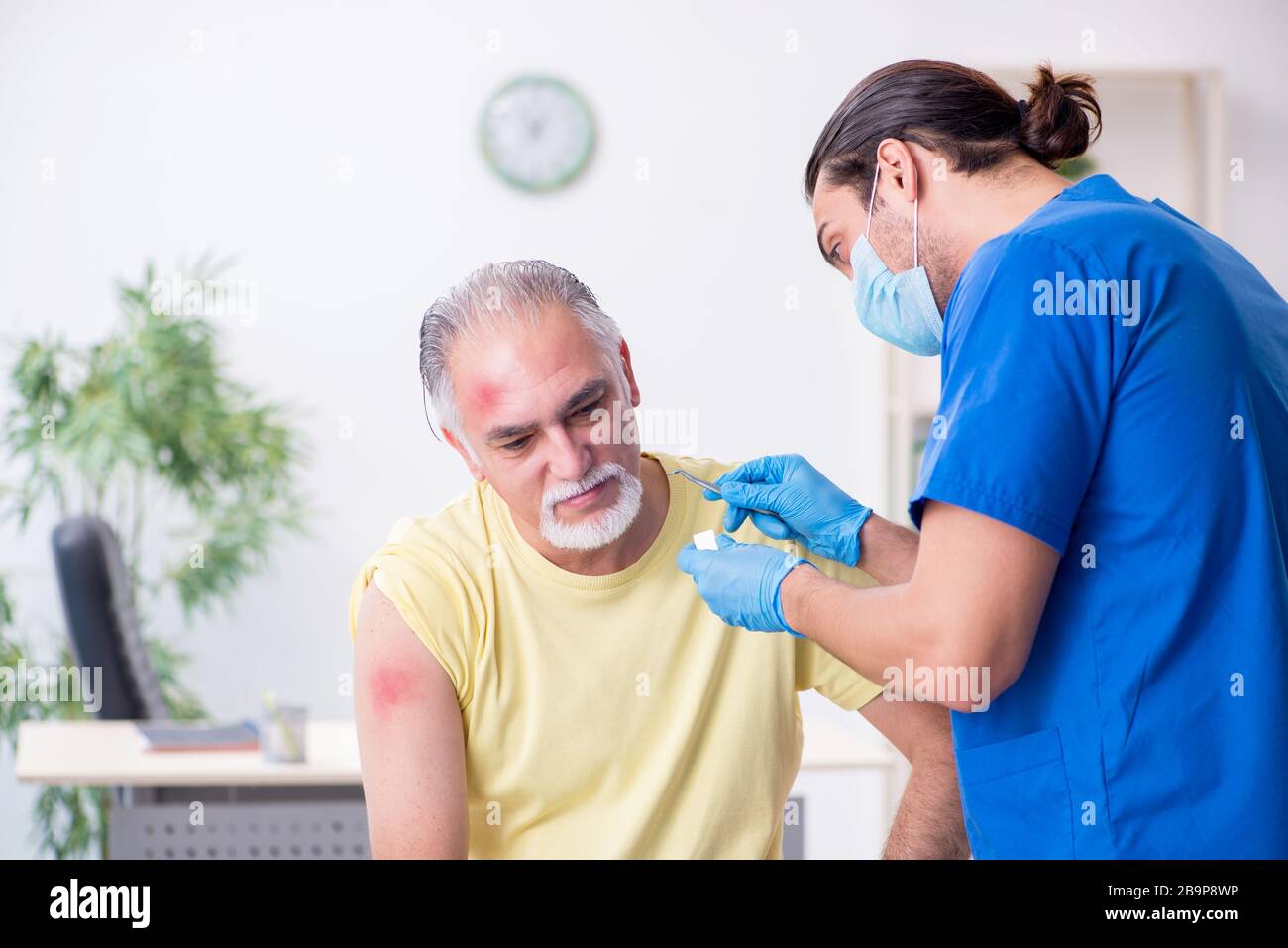 Injured old man visiting male doctor traumatologist Stock Photo - Alamy