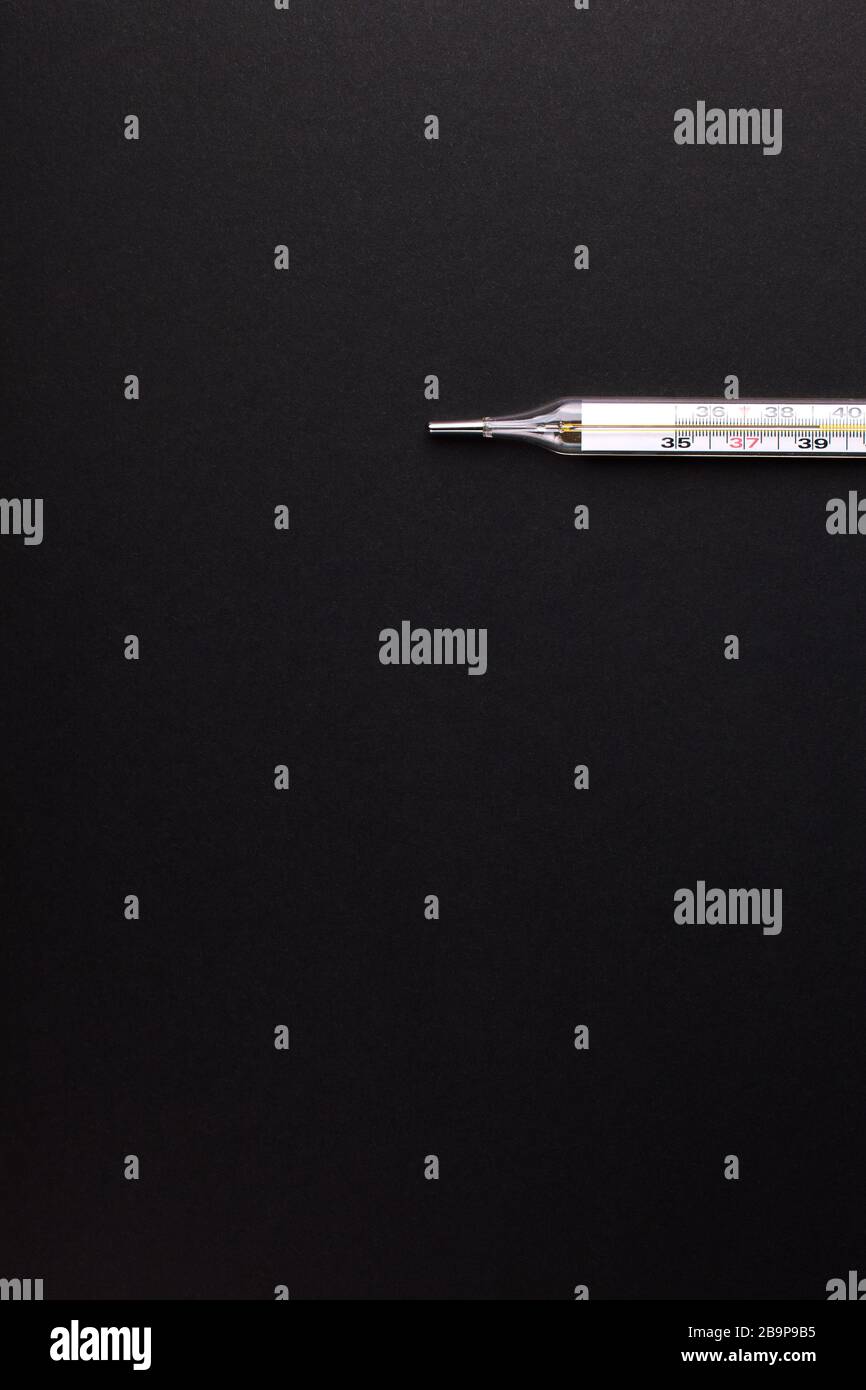 Medical thermometer with a temperature of 39 on a black paper ...