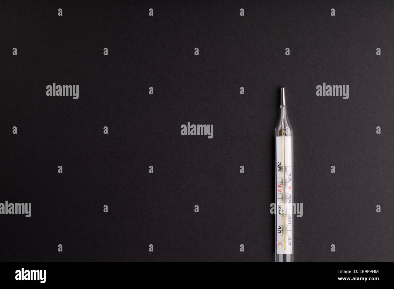 Medical thermometer with a temperature of 39 on a black paper ...