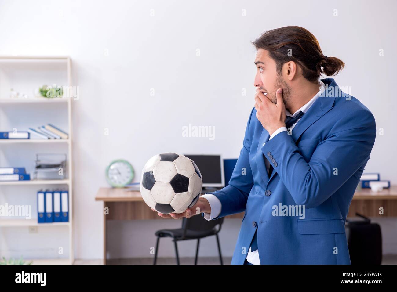 Young employee playing football in the office Stock Photo - Alamy