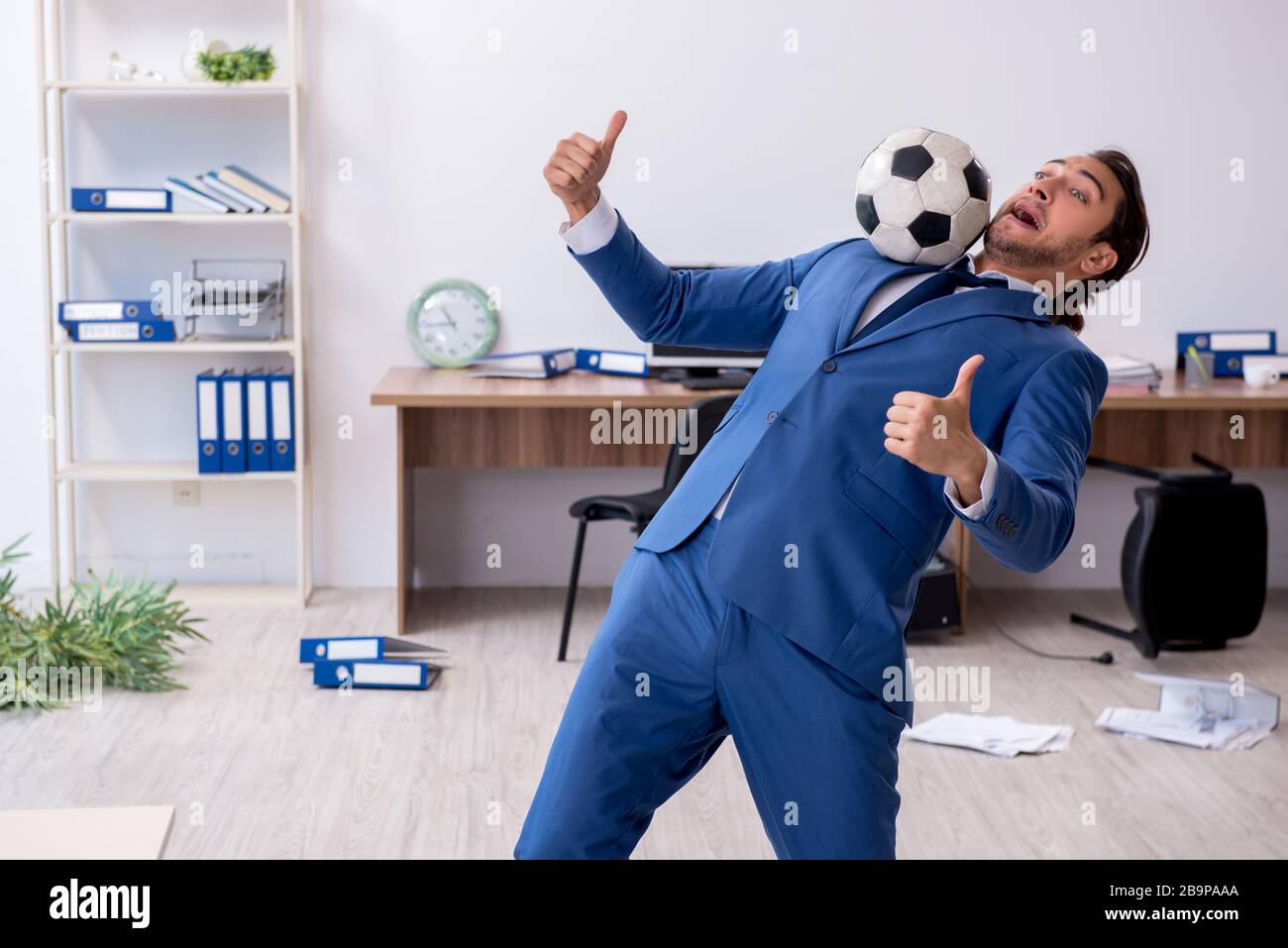 Young employee playing football in the office Stock Photo - Alamy
