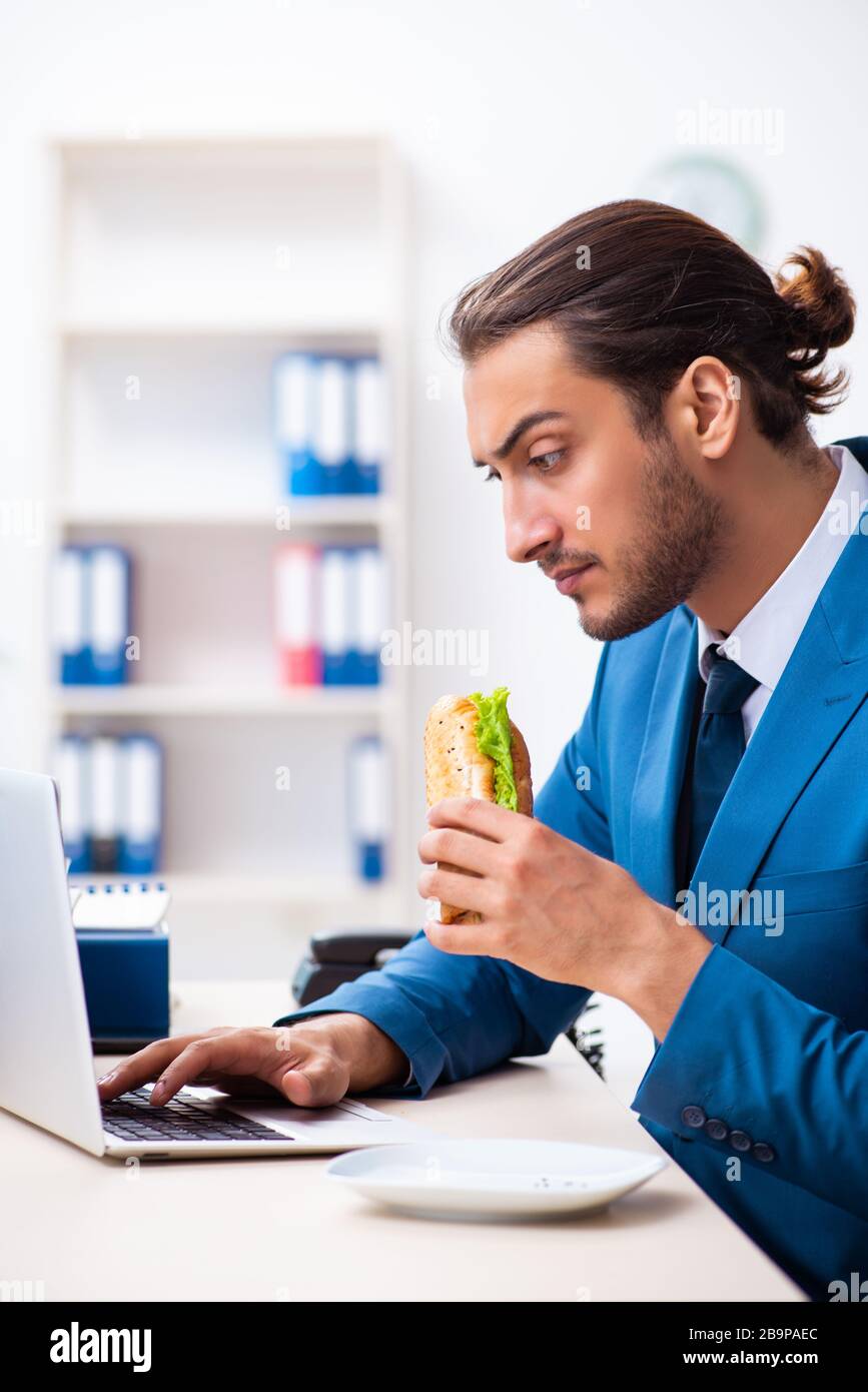 Young employee having breakfast at workplace Stock Photo - Alamy
