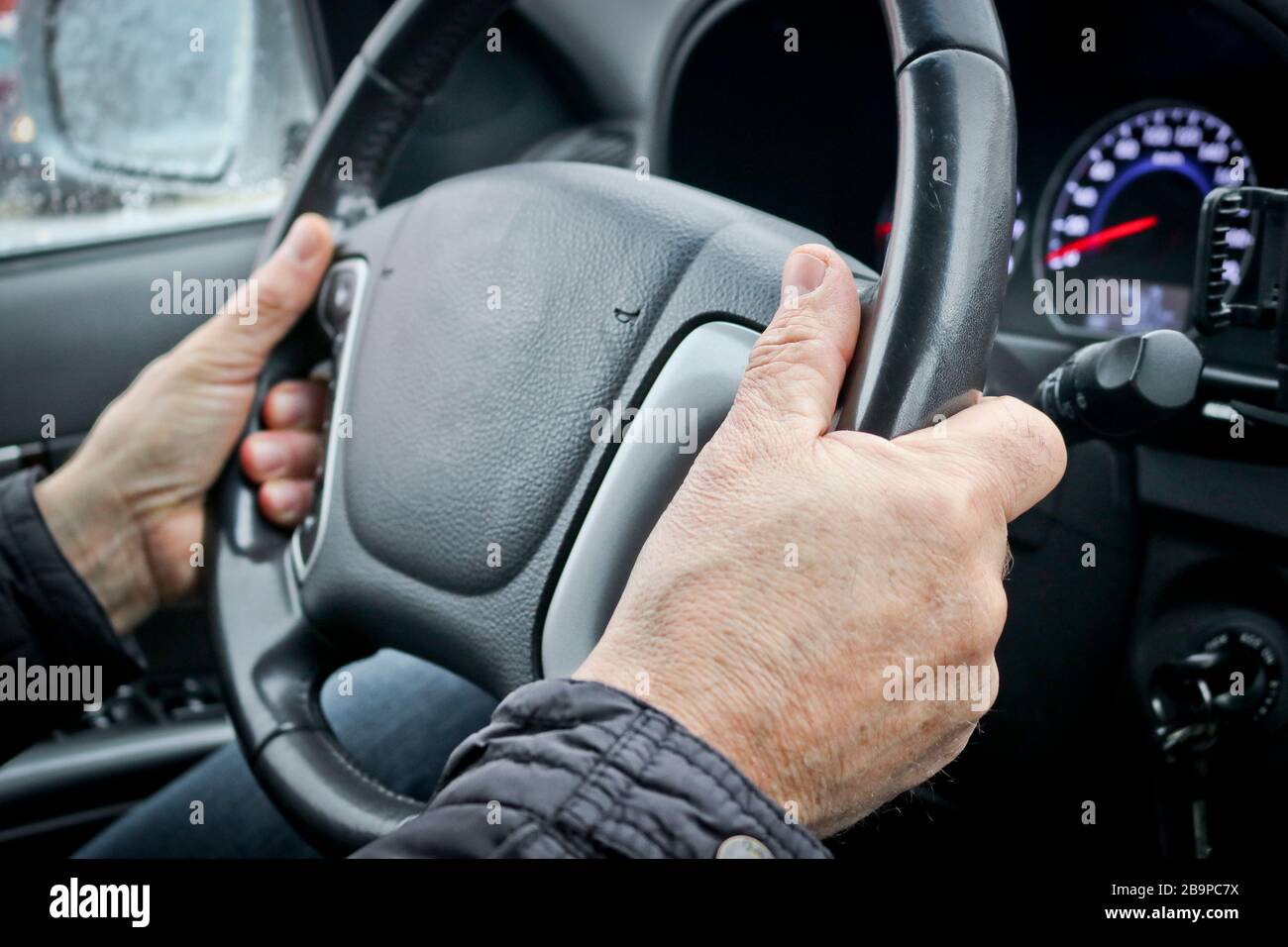 Men's hands on the steering wheel of a car. The driver controls the car ...