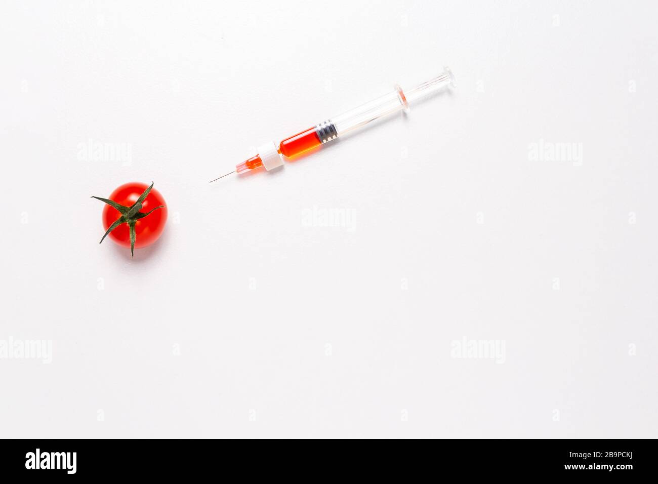 GMO vegetables. Red tomato and dye injection on light background ...
