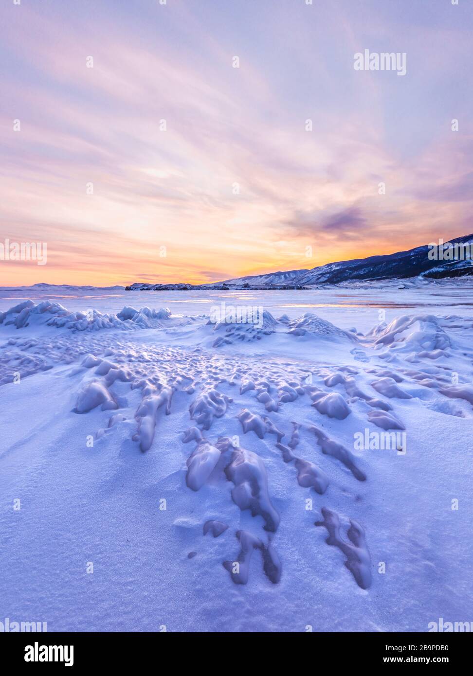 Frozen winter landscape of ice on lake Baikal during a colorful sunset ...