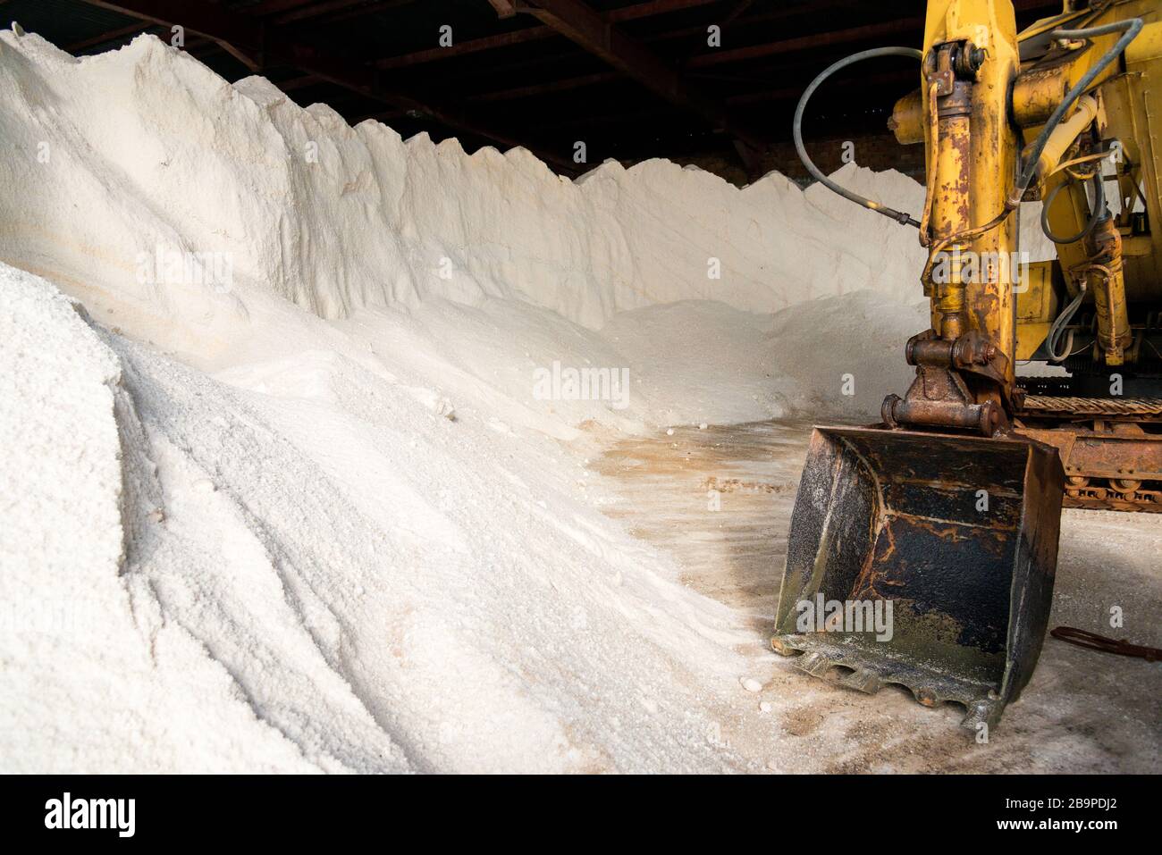 salt production - pile of salt and excavator at saltworks - selective ...
