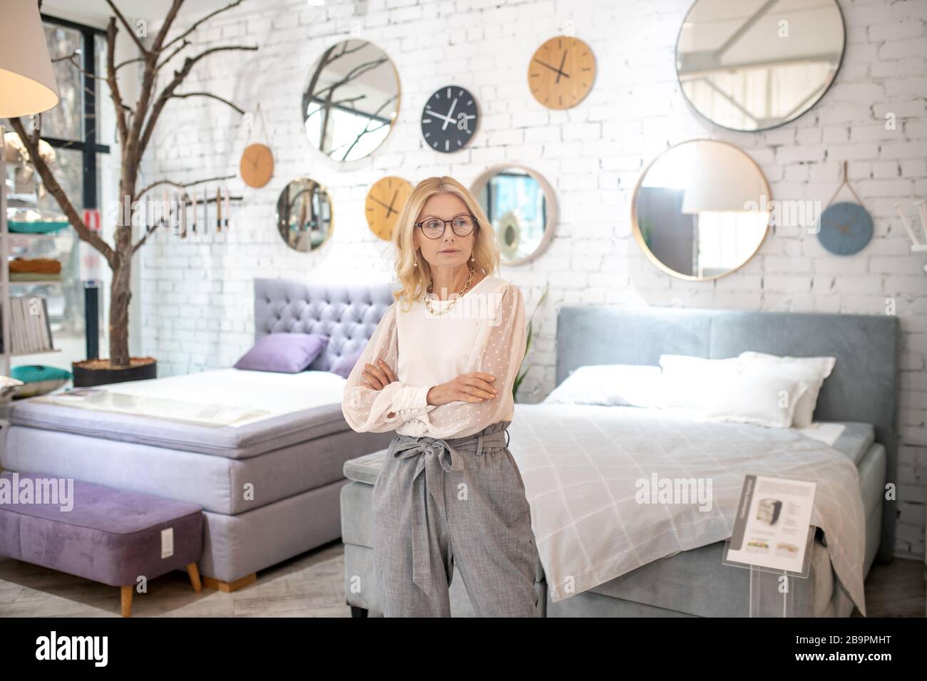 Serious woman standing indoors with hands folded over her chest Stock ...