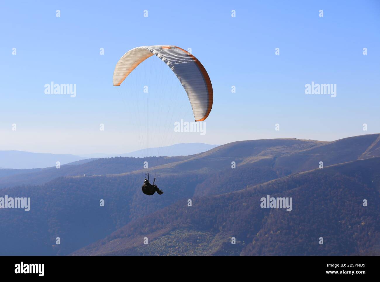 flying paraglider in air over mountains Stock Photo - Alamy