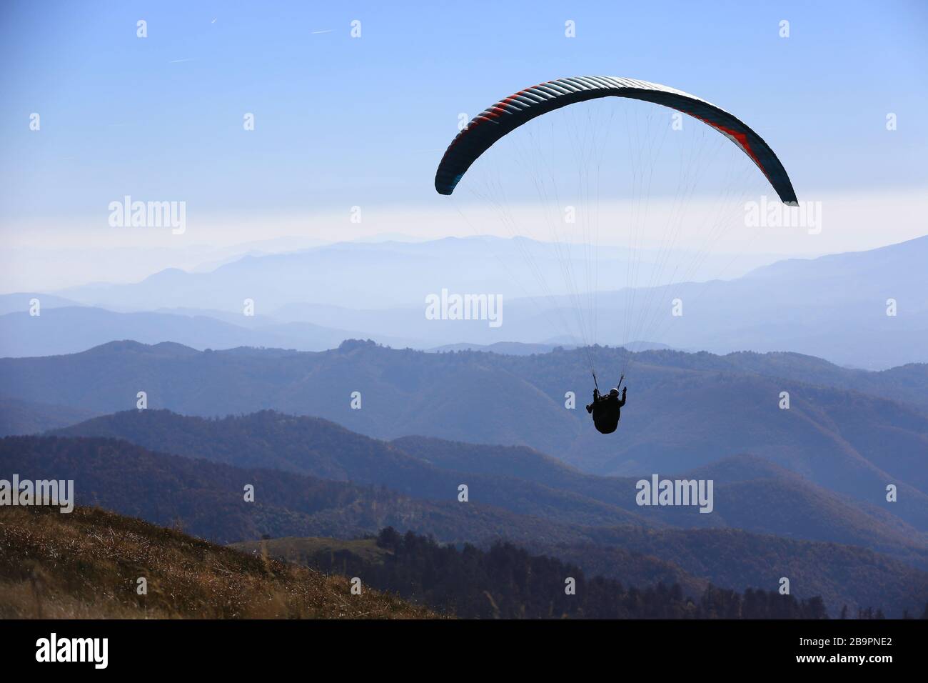scene with flying paraglider over mountain valley Stock Photo - Alamy