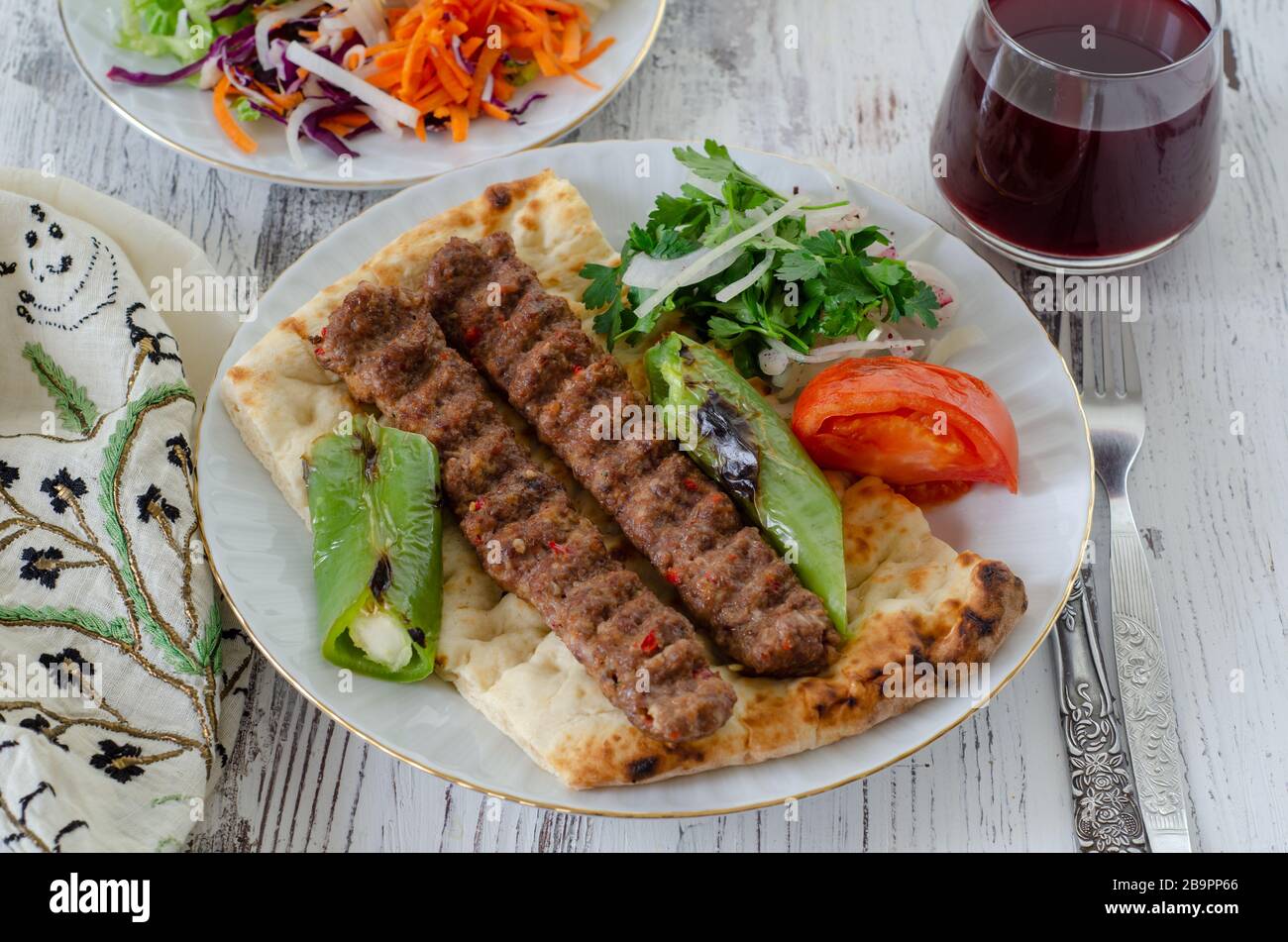 Traditional Adana Kebap with tomato and salad on a flatbread as top ...