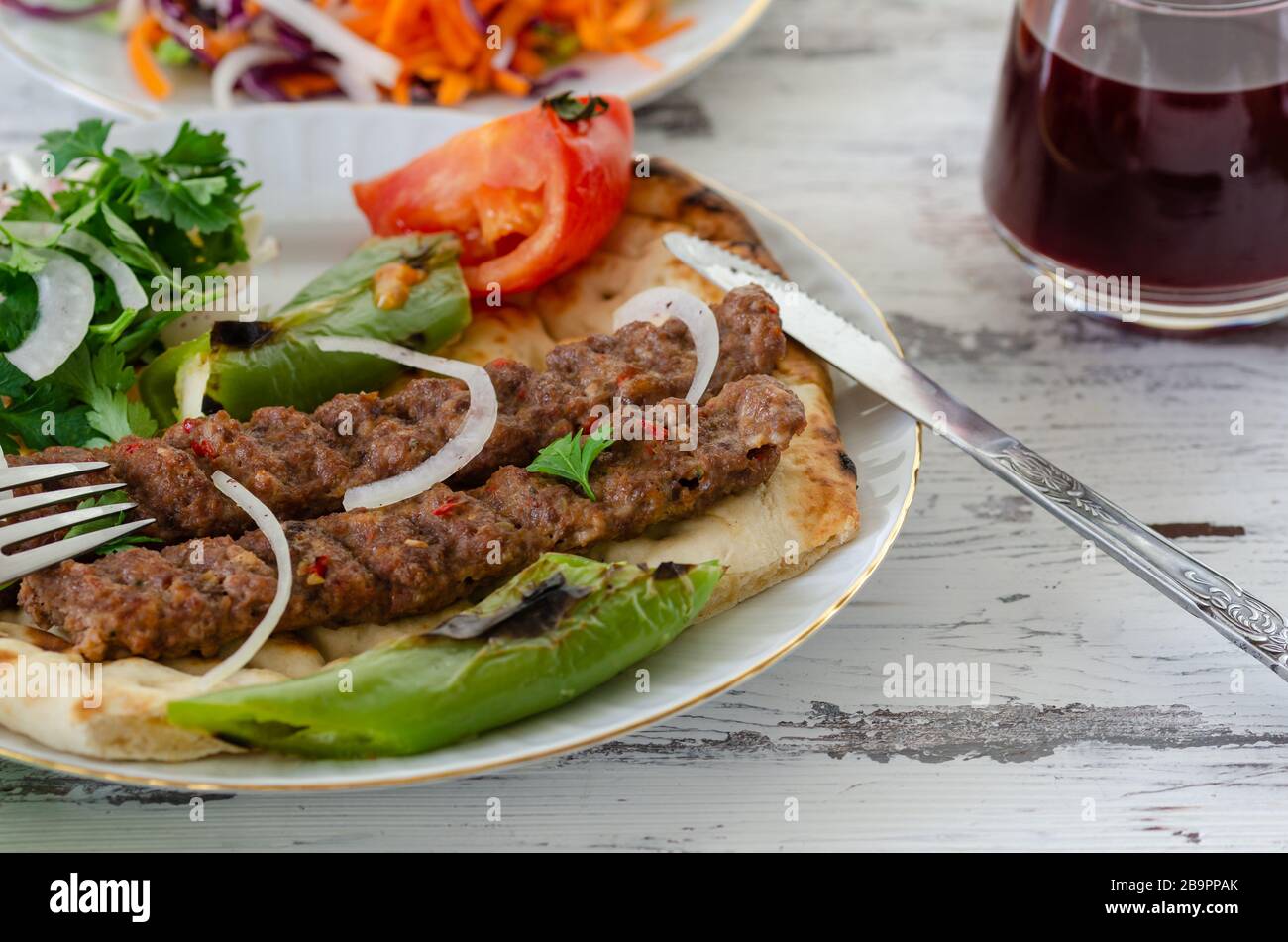 Traditional Adana Kebap with tomato and salad on a flatbread as top ...