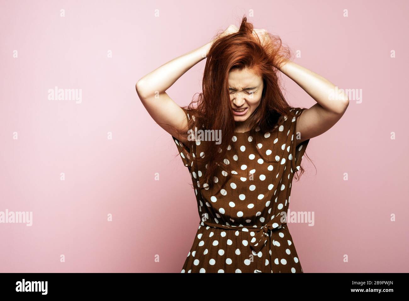 The female portrait isolated on pink studio backgroud. Anger. The young ...