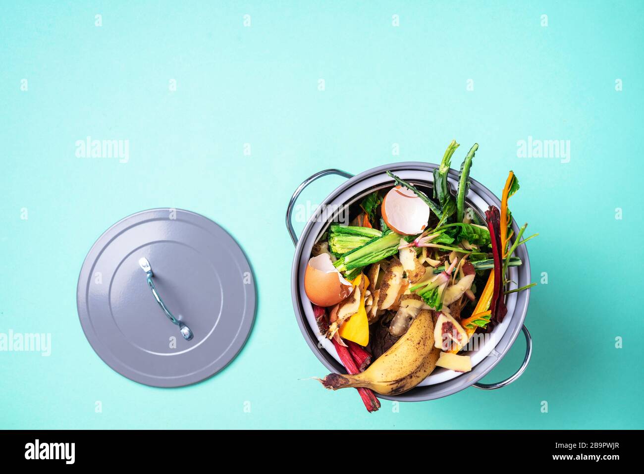 Peeled vegetables on chopping board, white compost bin on blue ...