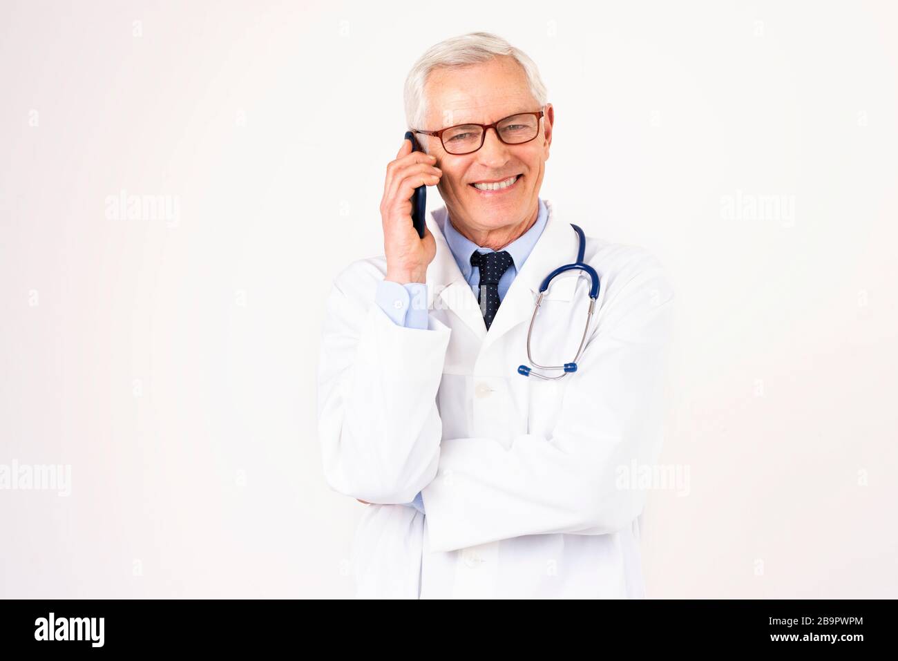 Portrait shot of senior male doctor using mobile phone while talking ...