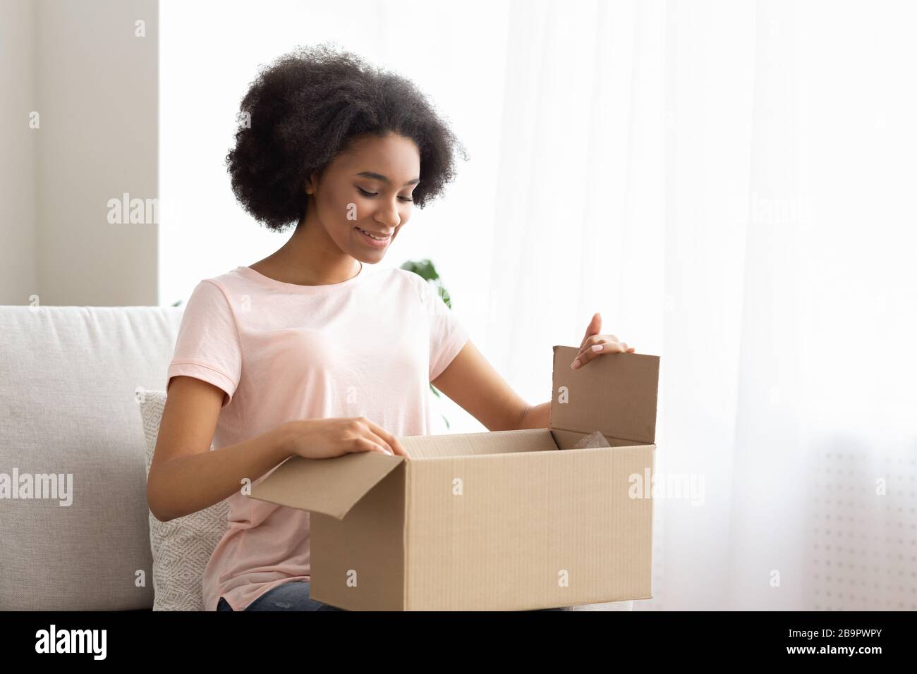 Satisfied young woman customer sit on sofa, unpack package parcel Stock ...