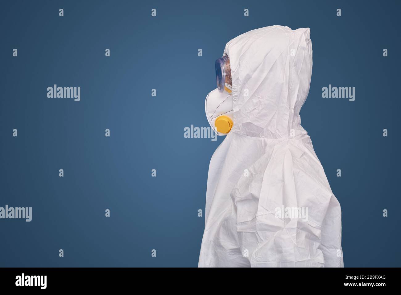 Woman doctor in white hazmat suit standing against blue background ...