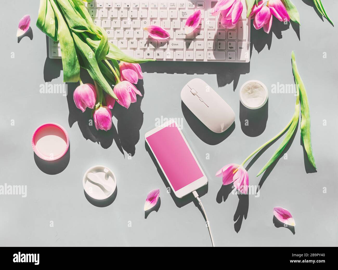 Female desktop with light pink tulips flowers bunch, cosmetics, PC ...