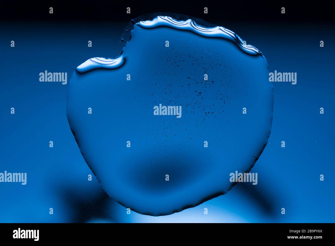 Large and flat liquid drops with granules underneath on a glass plate ...