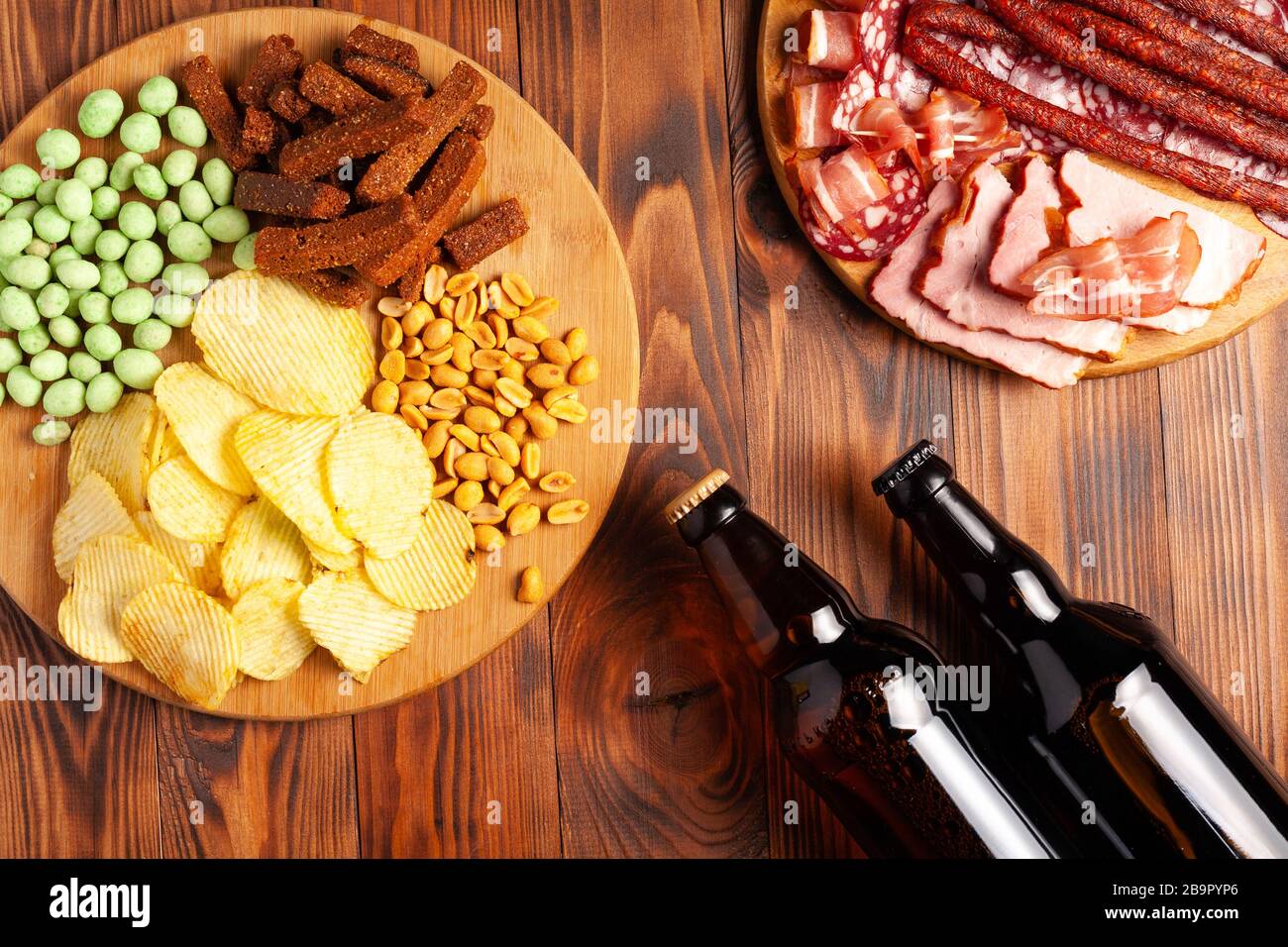 Two bottles of beer and a variety of snacks for every taste on a wooden ...