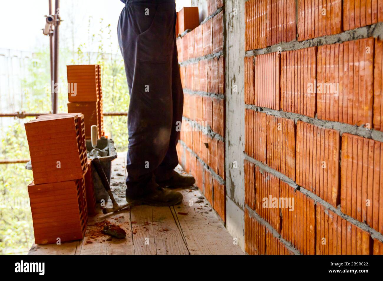 Mason, bricklayer worker is using red blocks to mount a wall at ...
