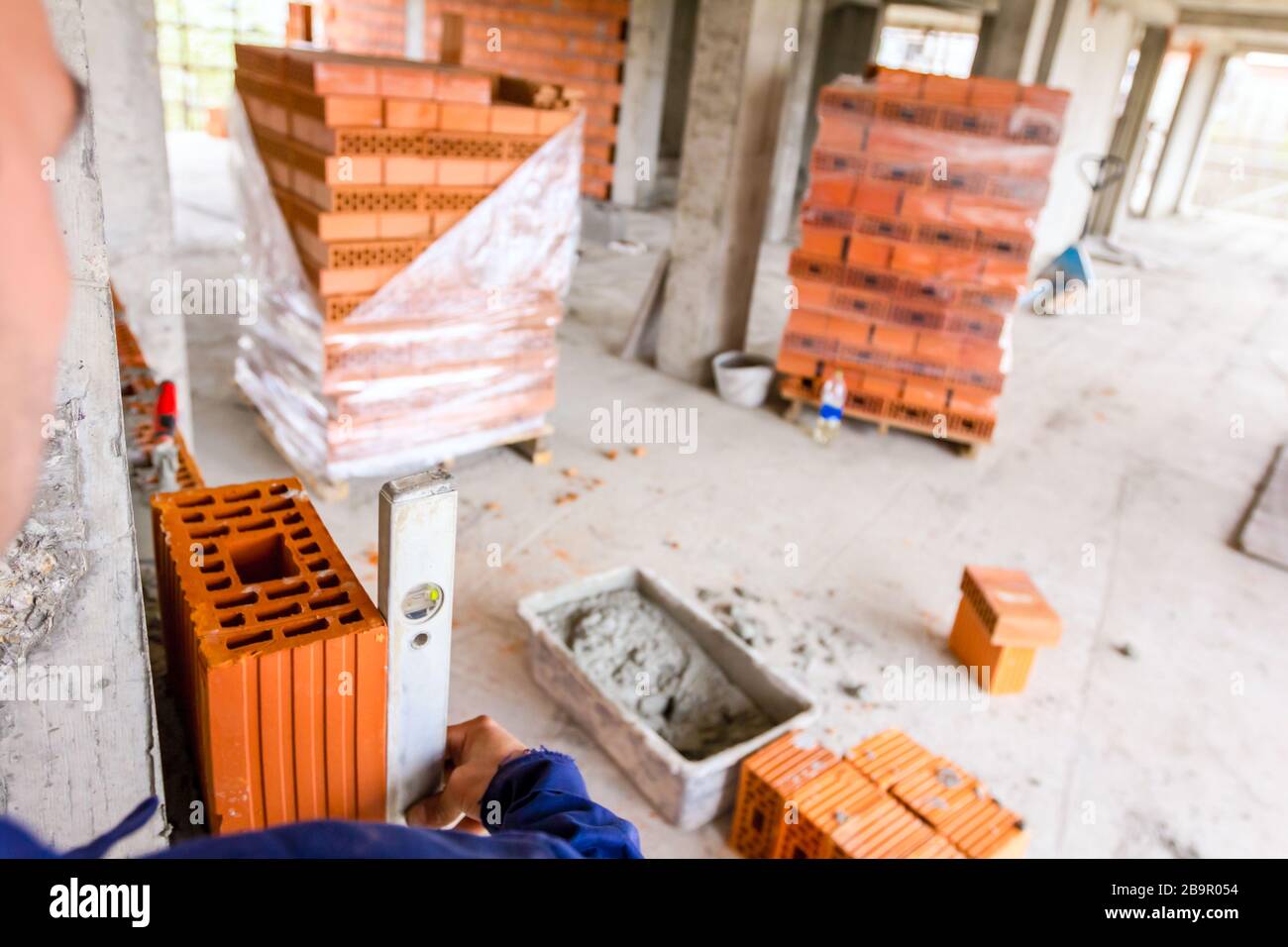 Builder is using a spirit level to check new red brick wall made of red ...