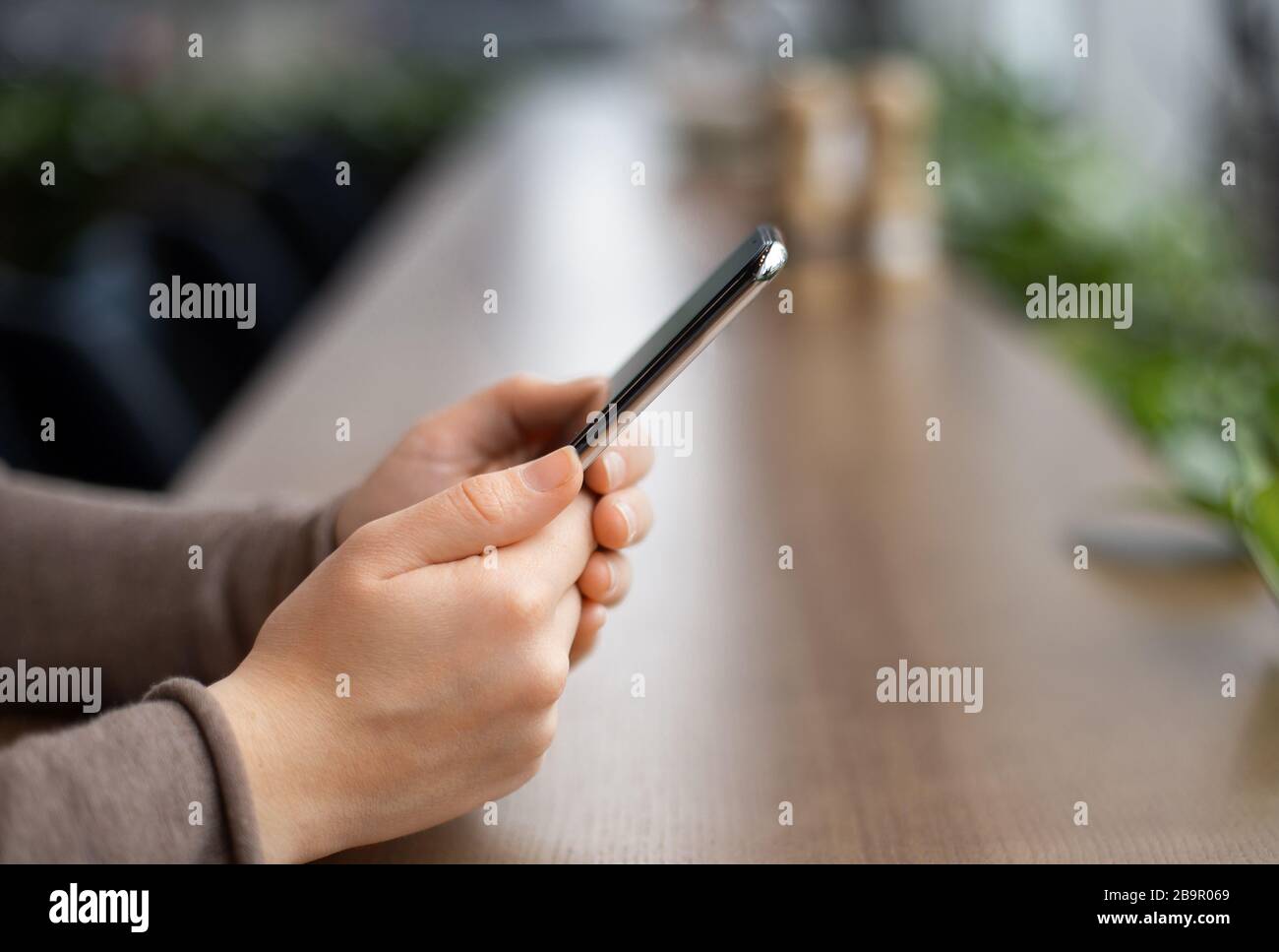 Female hands holding cell phone watching video during coffee break ...