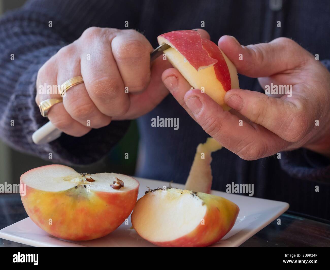 Old man hands peeling organic red Pink Lady apple outside over a bowl ...
