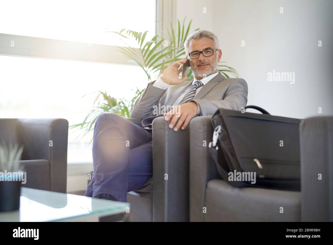 Corporate executive on cellphone waiting in lounge Stock Photo - Alamy