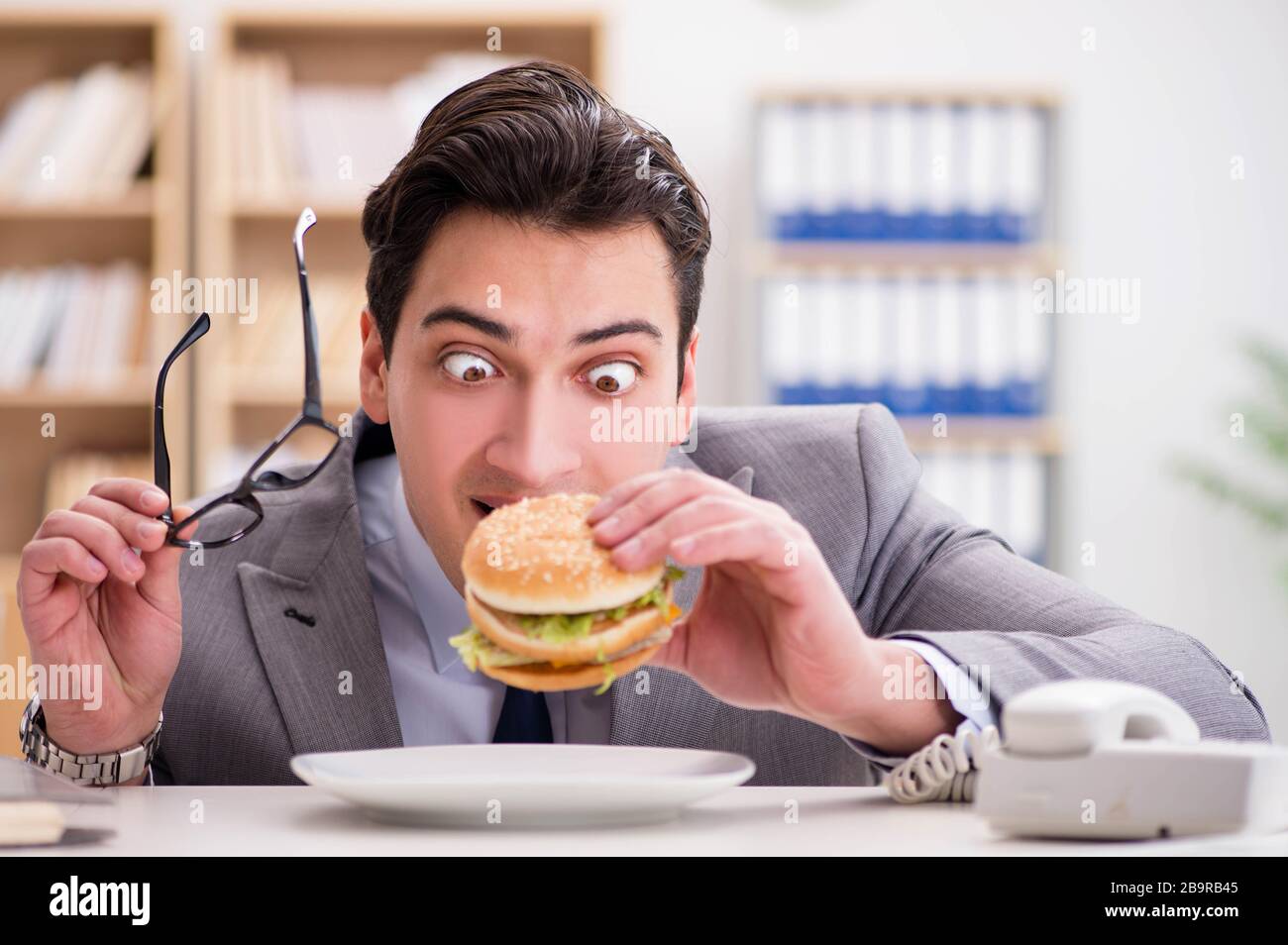 The hungry funny businessman eating junk food sandwich Stock Photo - Alamy