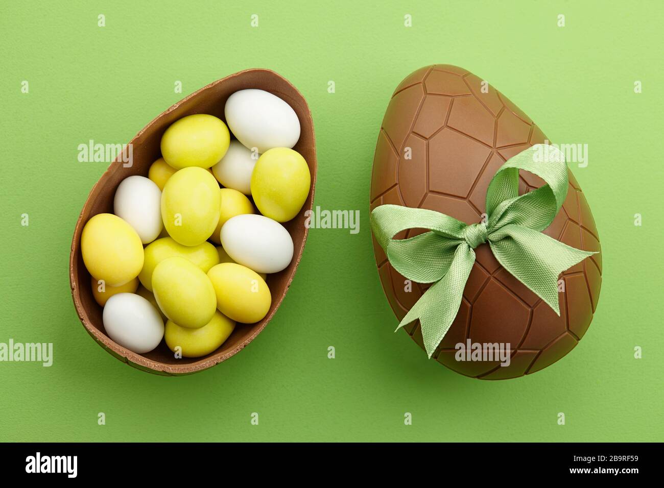 Chocolate Easter egg present with colorful candies on green background ...