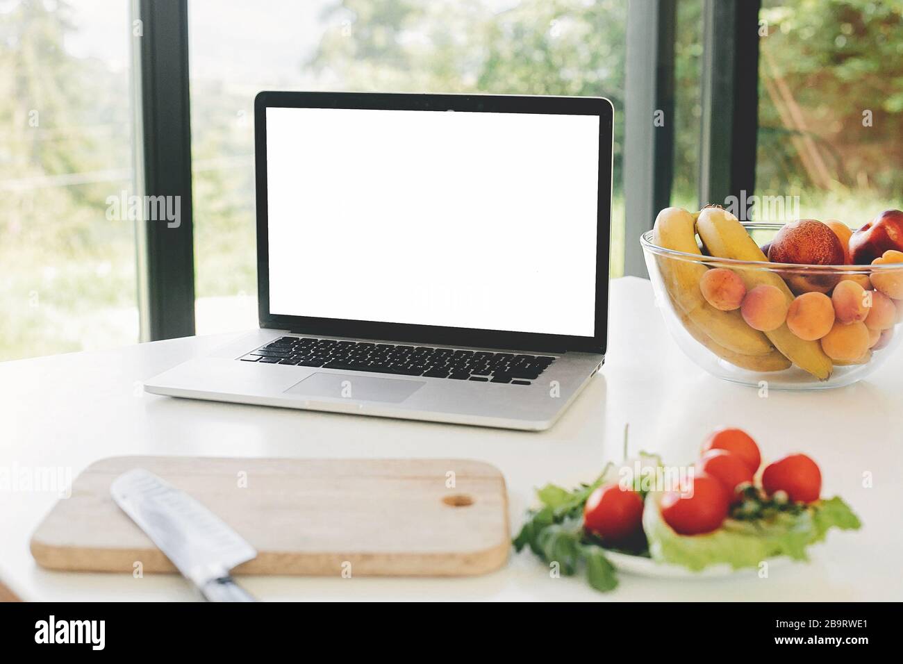 Food blog. Laptop with blank white screen and vegetables, knife and ...