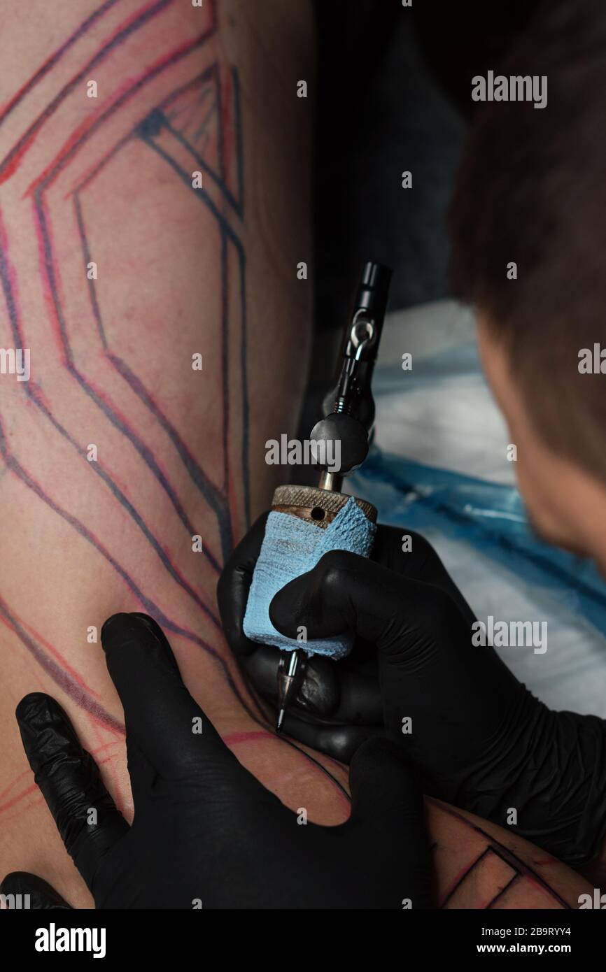 Professional tattoo artist makes tattoo on man leg. Process. Introduces ...