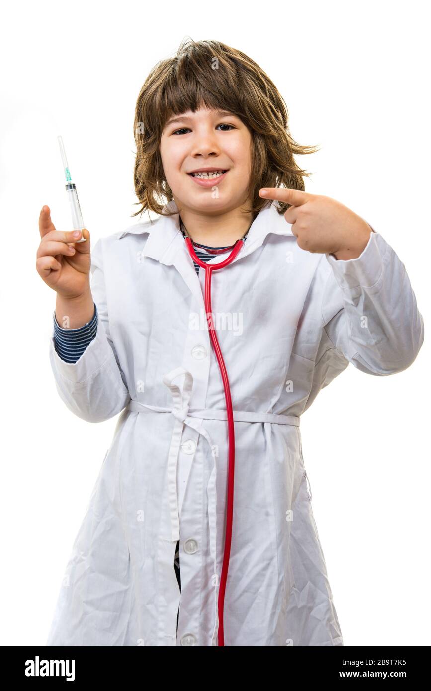 Happy kid boy in doctor coat pointing to a syringe isolated on white ...