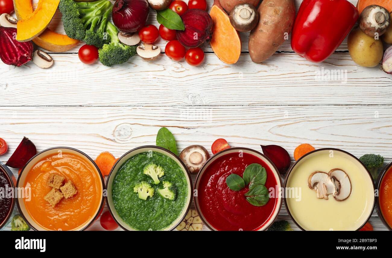 Vegetable soups and ingredients on white wooden background, top view ...