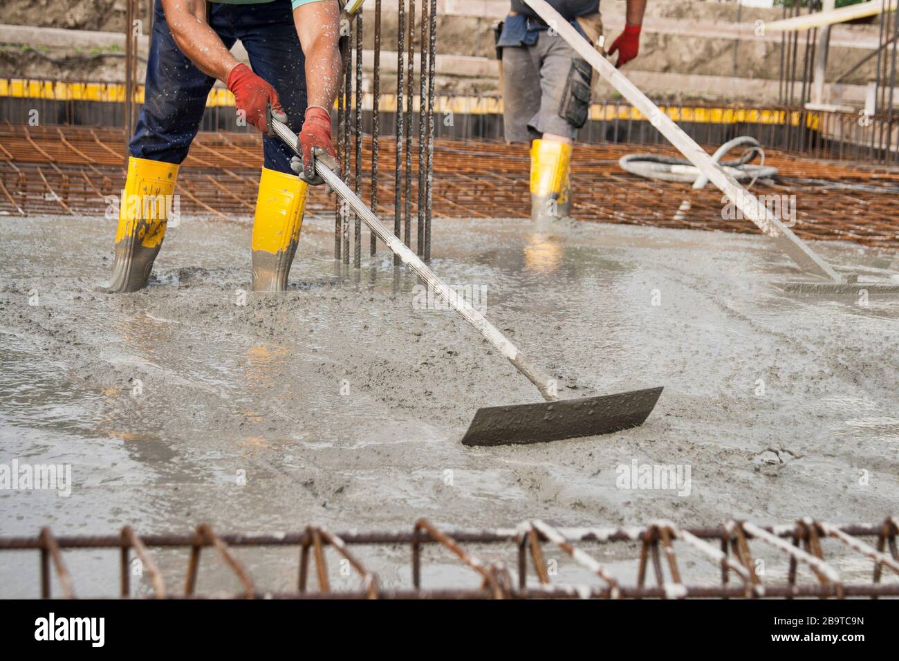 two bricklayers at work on a construction site during the laying of ...