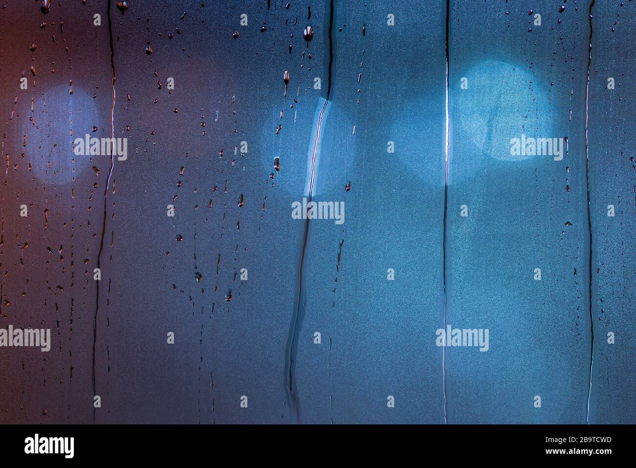an abstract background of night wet window glass with smudges in blue ...