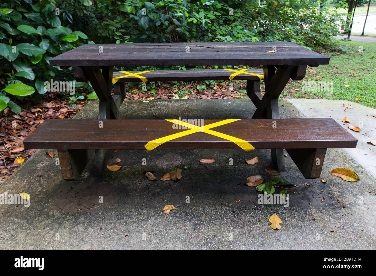 Outdoor sitting bench is pasted with a cross sign by a yellow tape to ...