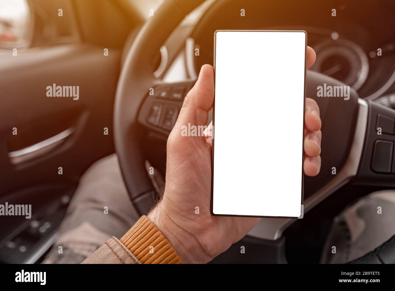 Smartphone blank screen mock up in driver's hand in front of the car ...