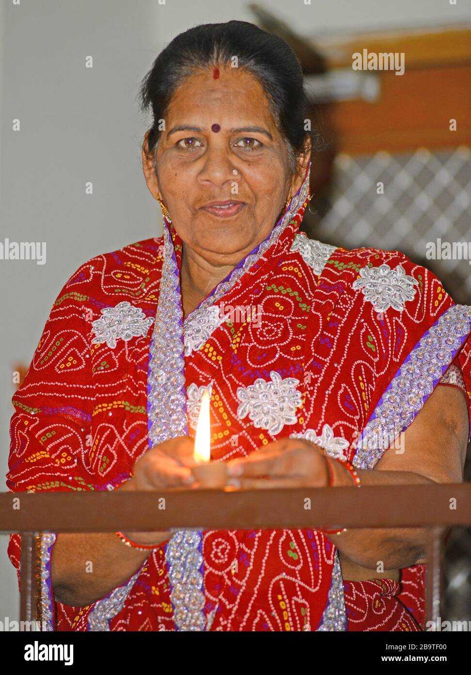 An Indian woman decorates the entrance of her home with earthen lamps ...